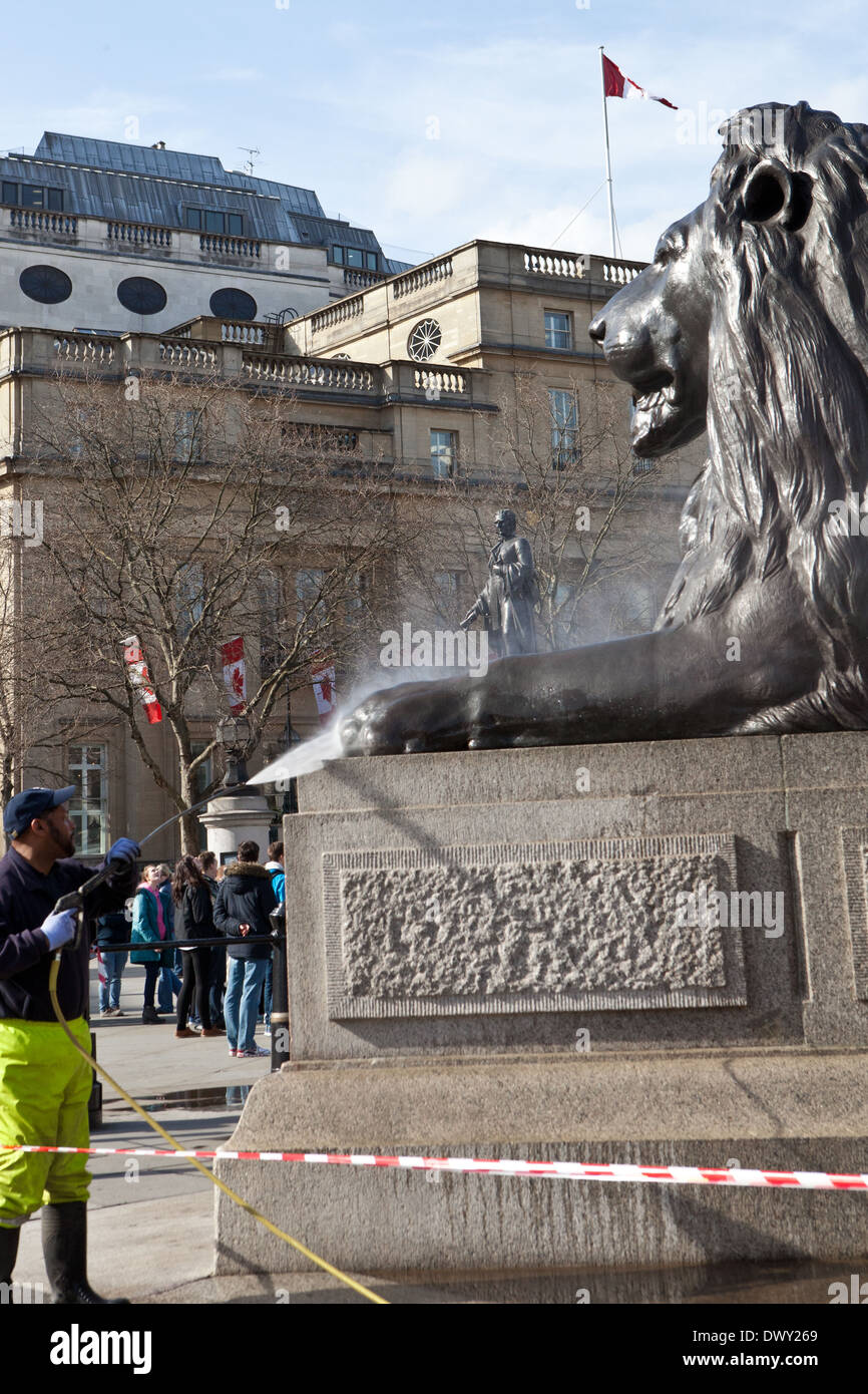 A man cleaning a bronze lion at Nelsons Column Stock Photo - Alamy
