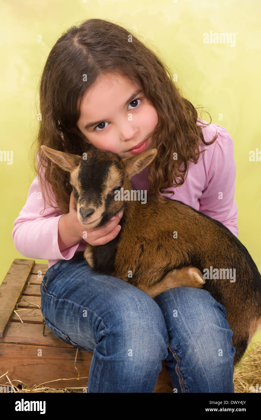 Little adorable girl hugging a newborn baby goat Stock Photo - Alamy