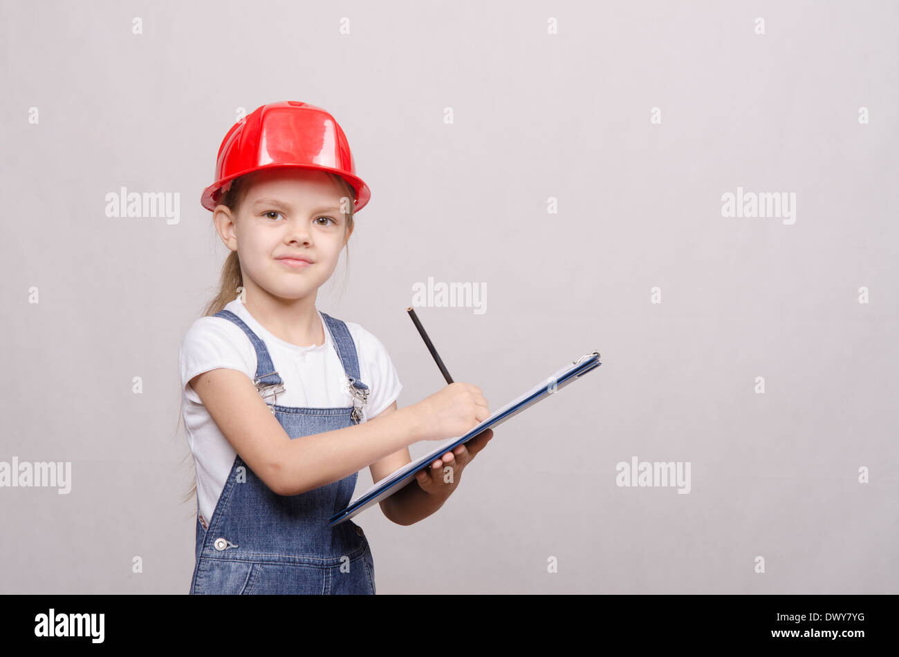 Girl engineer is a helmet folder and writes in folder Stock Photo - Alamy