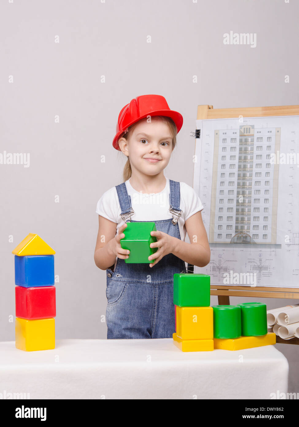 Girl playing in the Builder builds a set of cubes house. In the ...