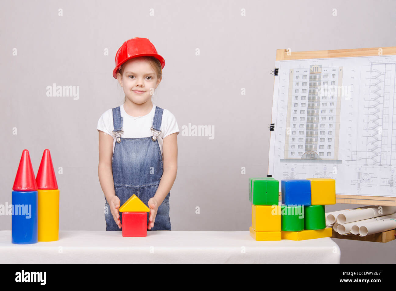 Girl playing in the Builder builds a set of cubes house. In the ...