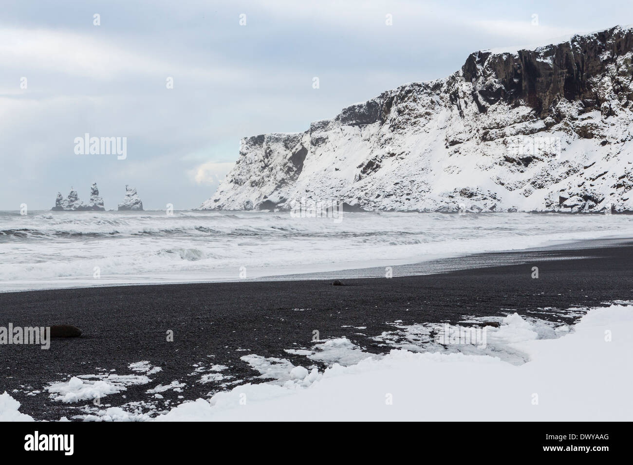 Basalt black sands and Reynisfjall Cliffs covered with fresh snowfall ...