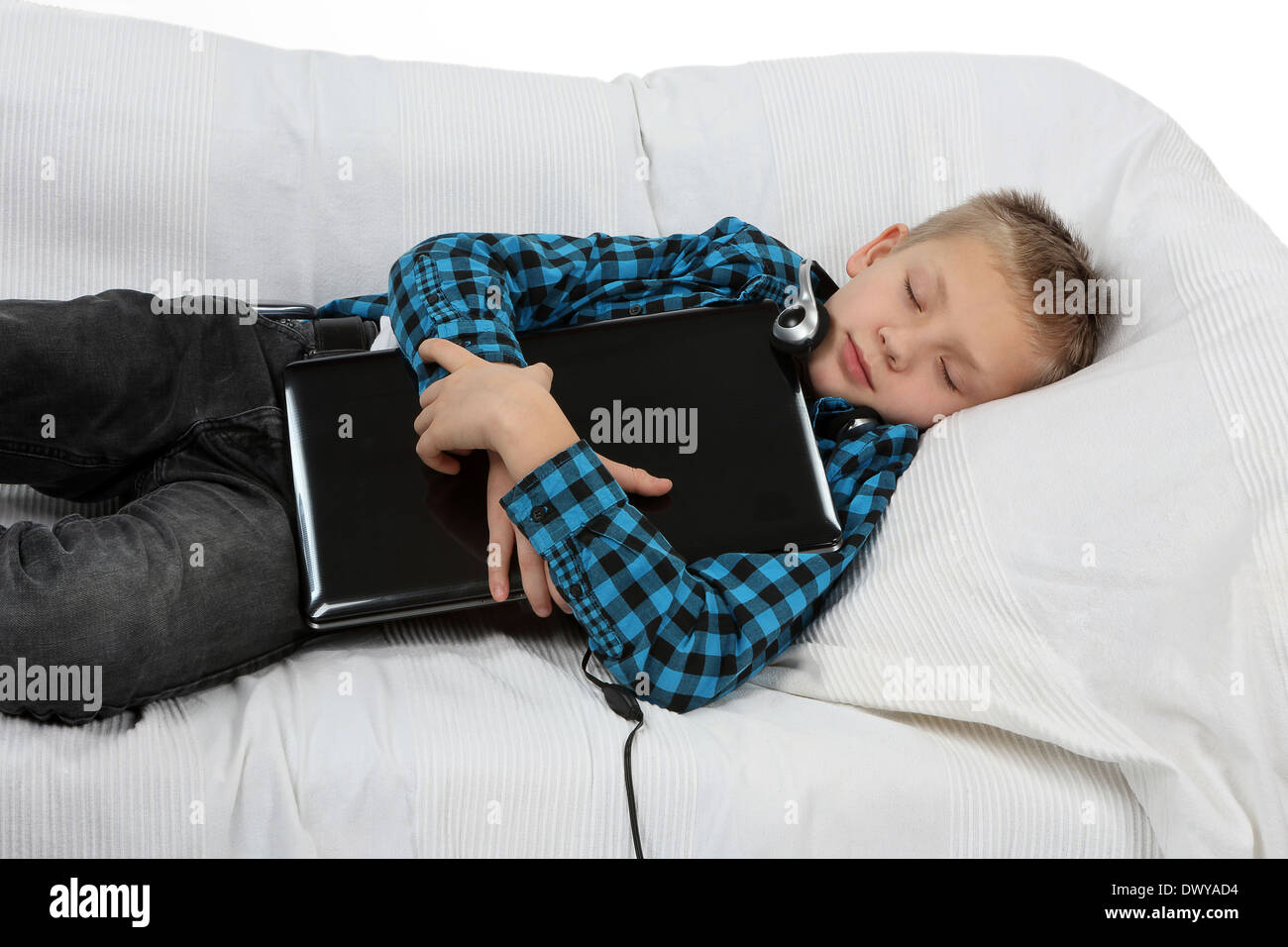 Teen boy sleeping on the couch with laptop computer and mobile phone in ...