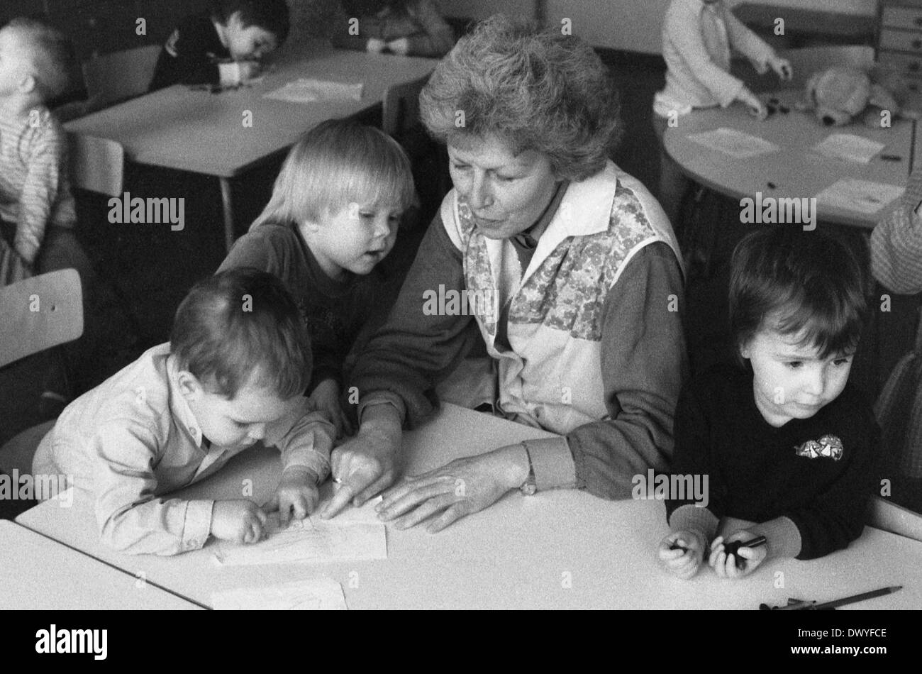 Berlin, GDR, teacher in a kindergarten drawing with young children ...