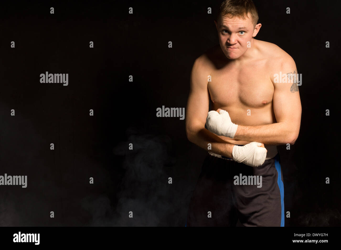 Strong muscular young boxer with a determined expression crouching ...