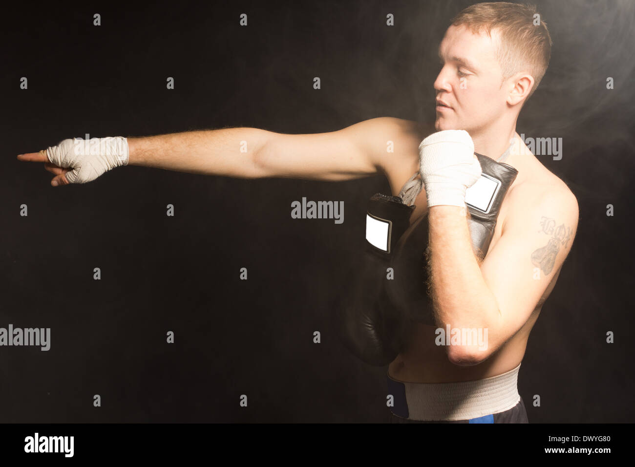 Muscular young boxer pointing with his bandaged hand extended in front ...