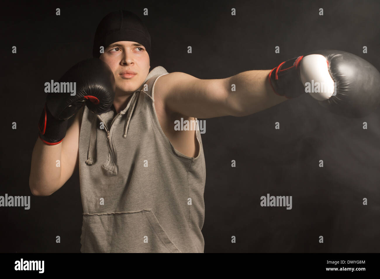 Young boxer throwing a punch with his gloved fist with a look of ...