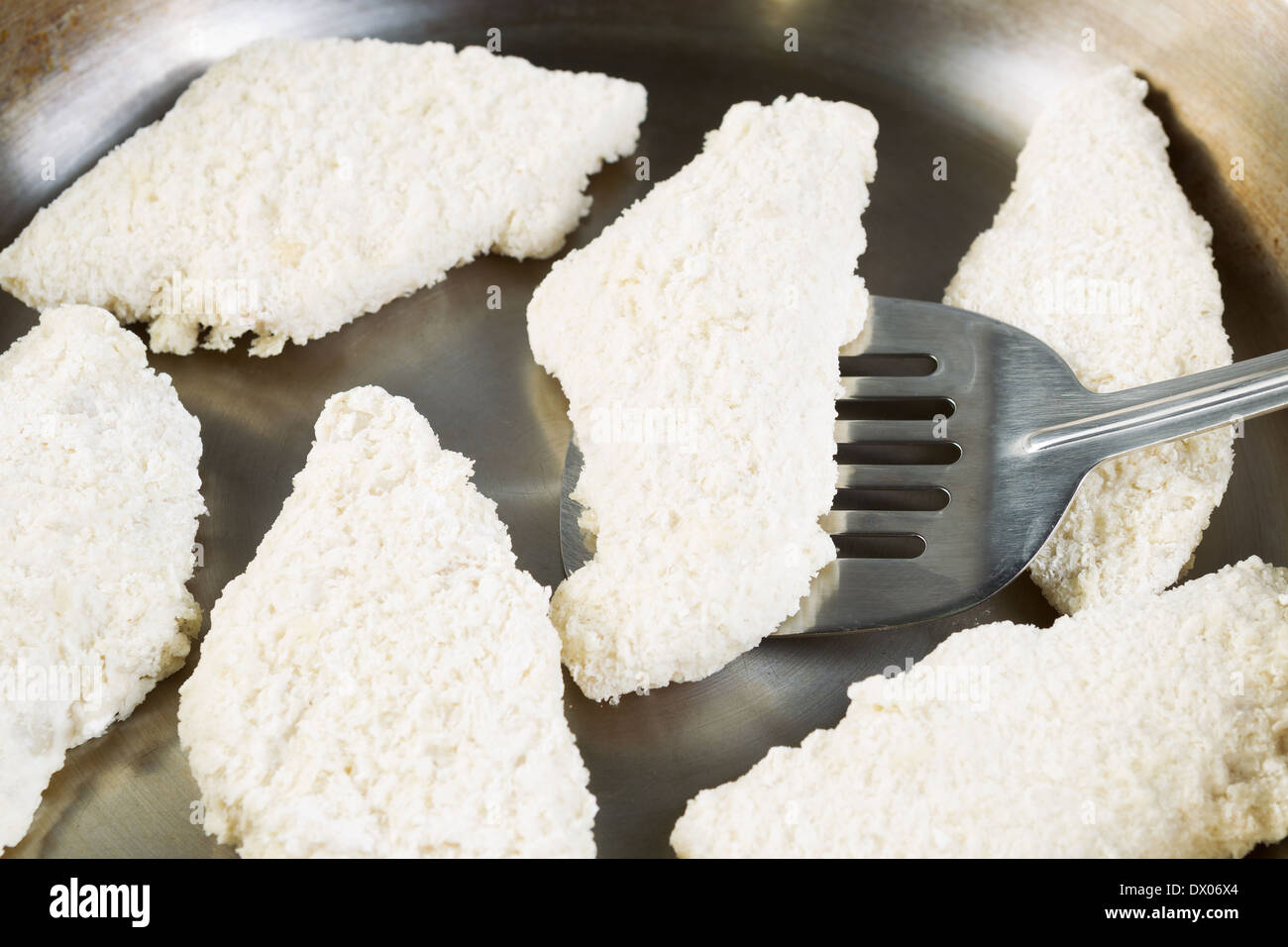 Horizontal photo of breaded coated fish placing place into stainless ...