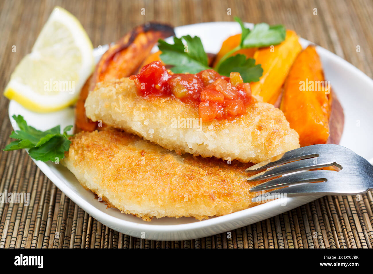 Closeup horizontal of golden crisp fried fish with salsa sauce on top ...