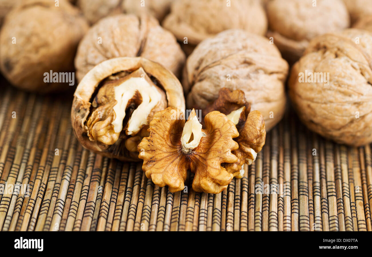 Close up horizontal photo of unshelled half of walnuts lying on bamboo ...
