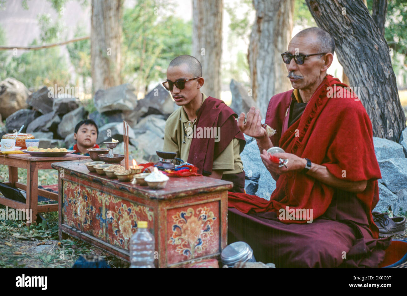 Monks sit at their folding puja prayer tables, burn incense and chant ...