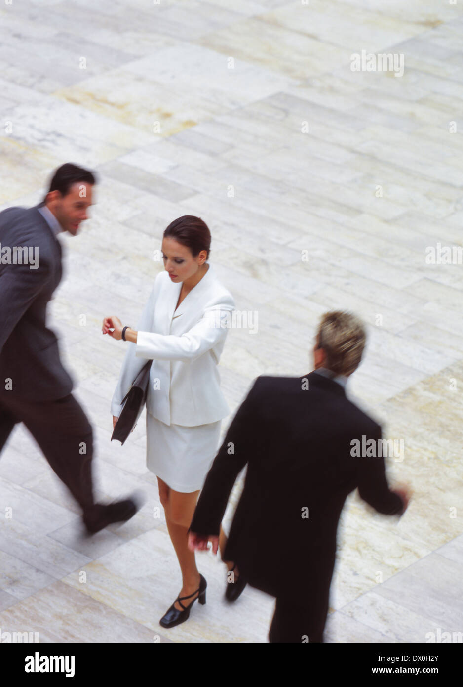 Business woman in costume looking at the clock, men running frantically ...