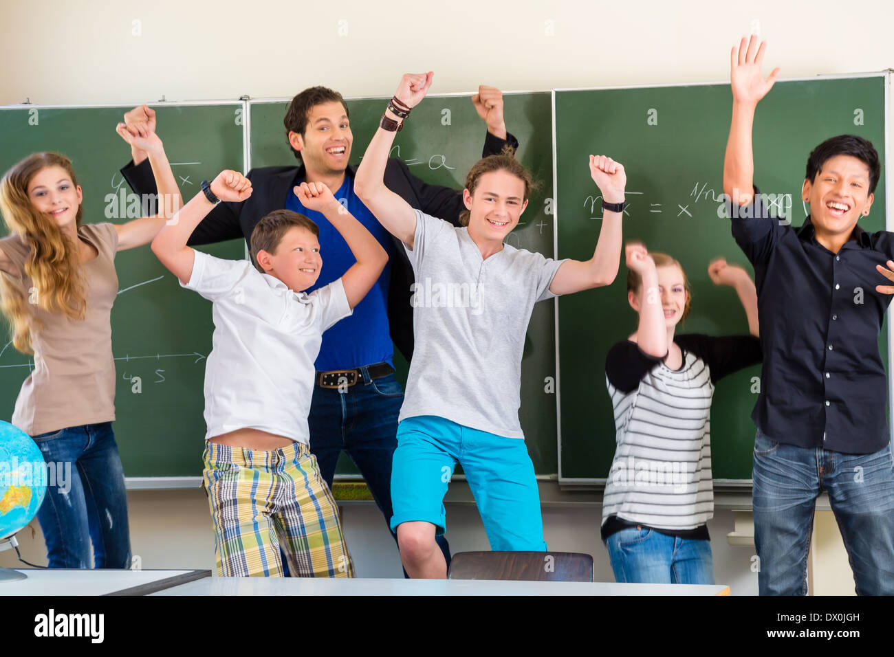 Successful Teacher and students jump in front of a blackboard with math ...