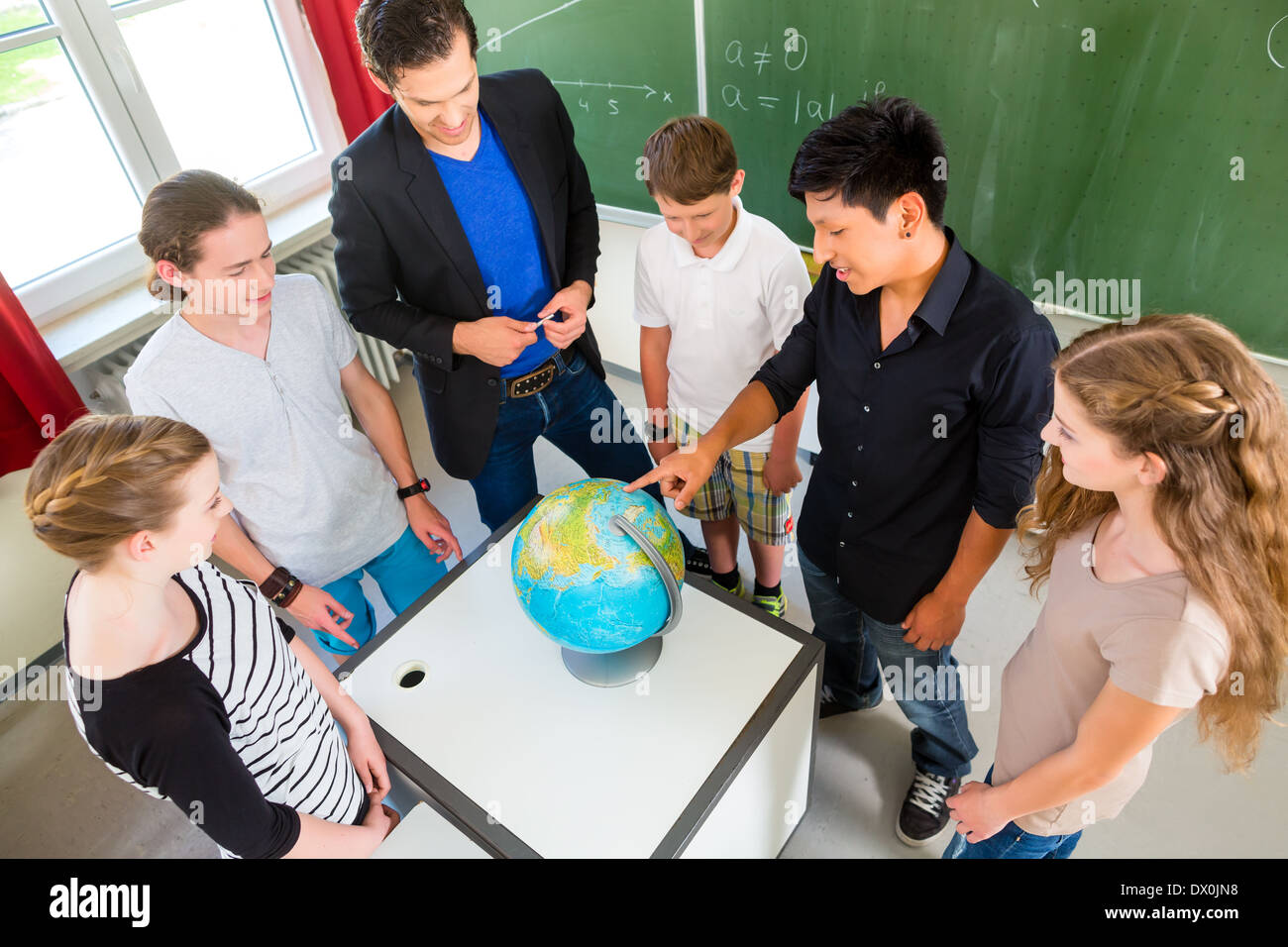 Students or pupils having group work while geography lesson and the ...