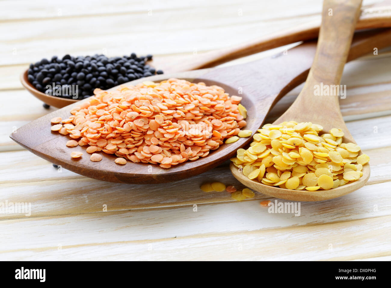 different kinds of lentils - red, yellow and black in wooden spoons ...