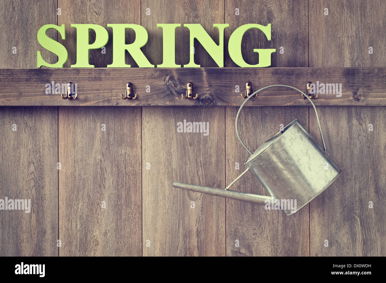 Watering can hanging in shed with the word Spring Stock Photo - Alamy