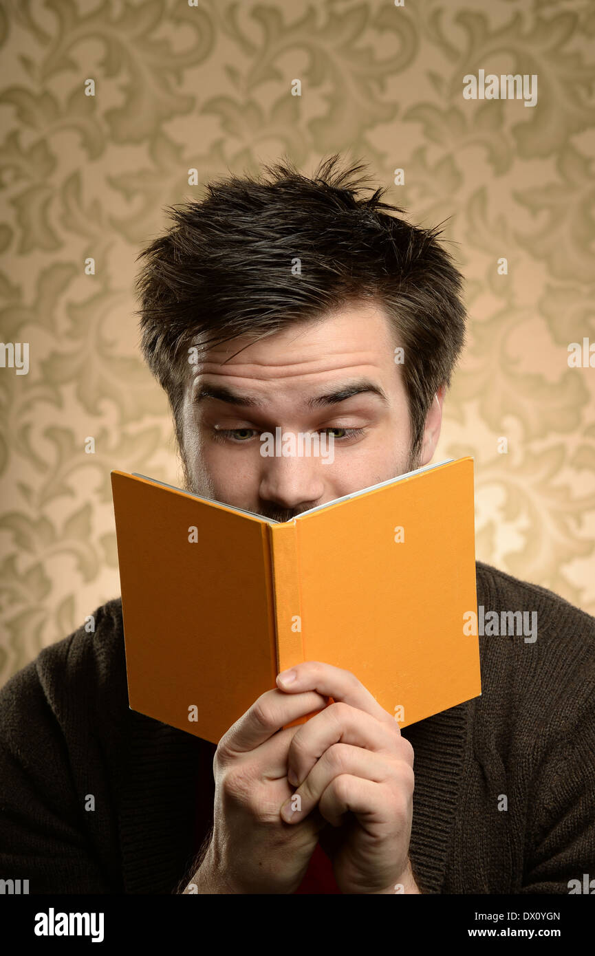 Portrait of young man showing surprise while reading over retro ...