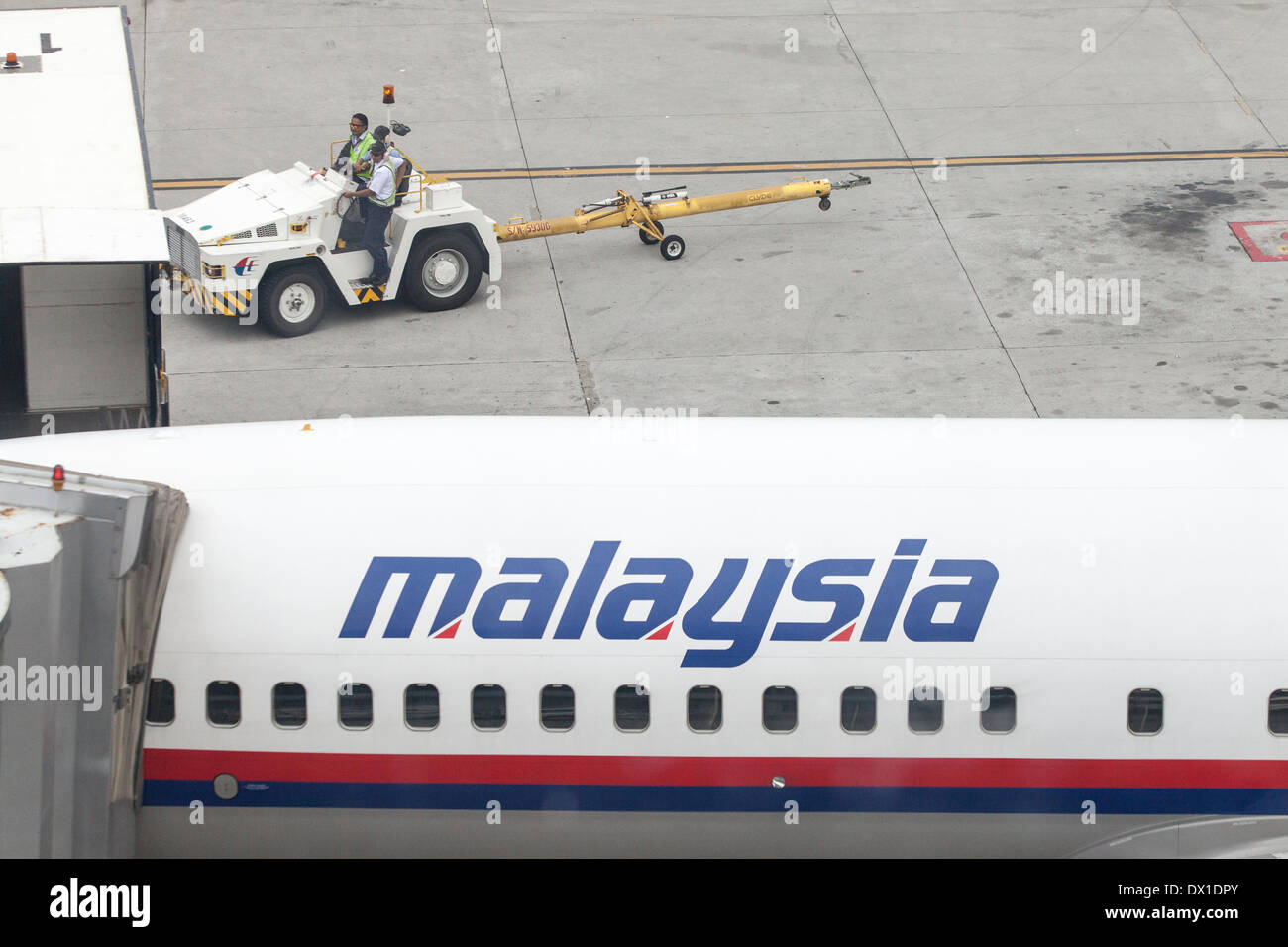 Ground crew drive by an aircraft operated by Malaysian Airline System ...