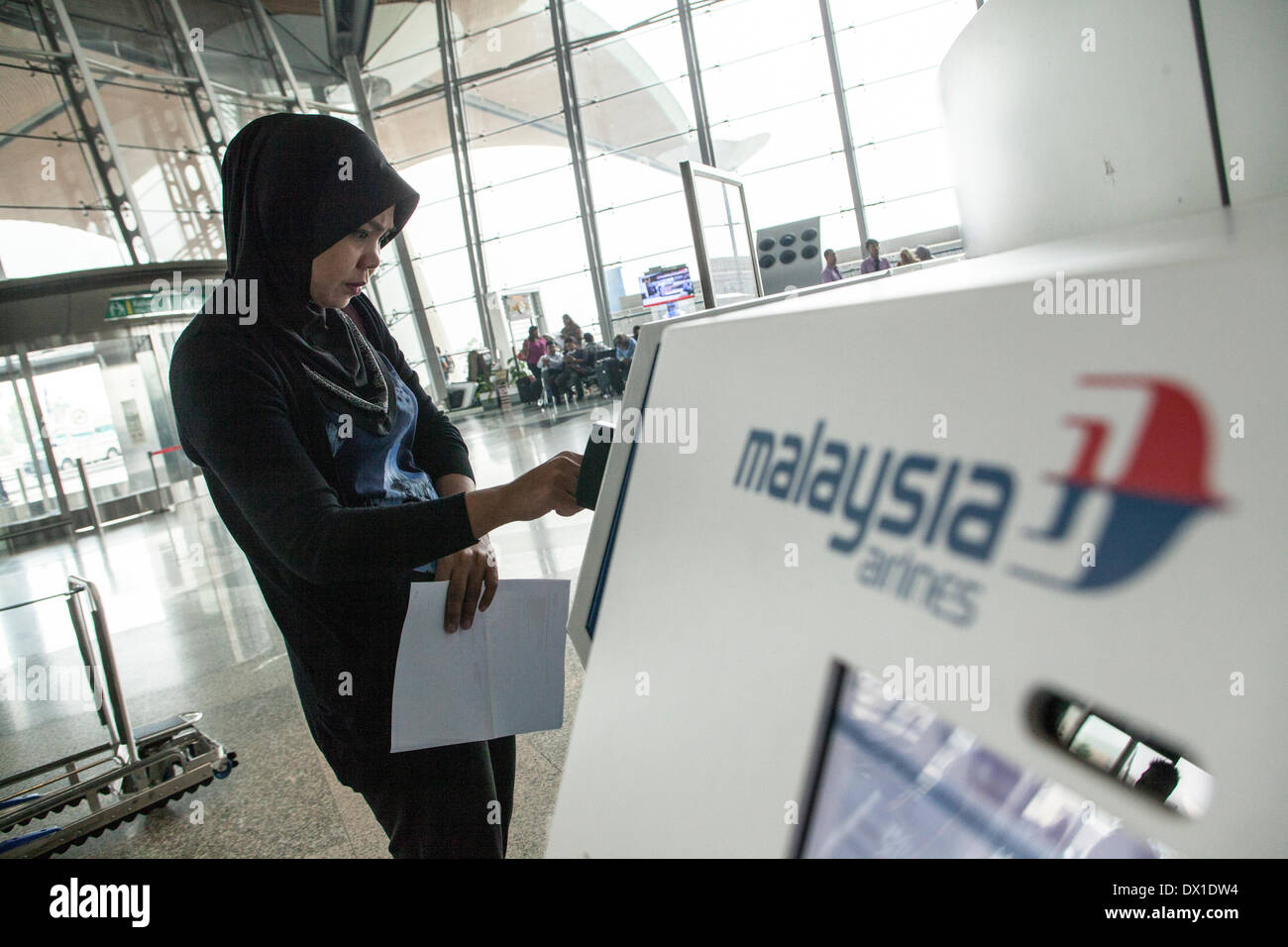 A passenger uses a self-service kiosk to check in for a Malaysian ...