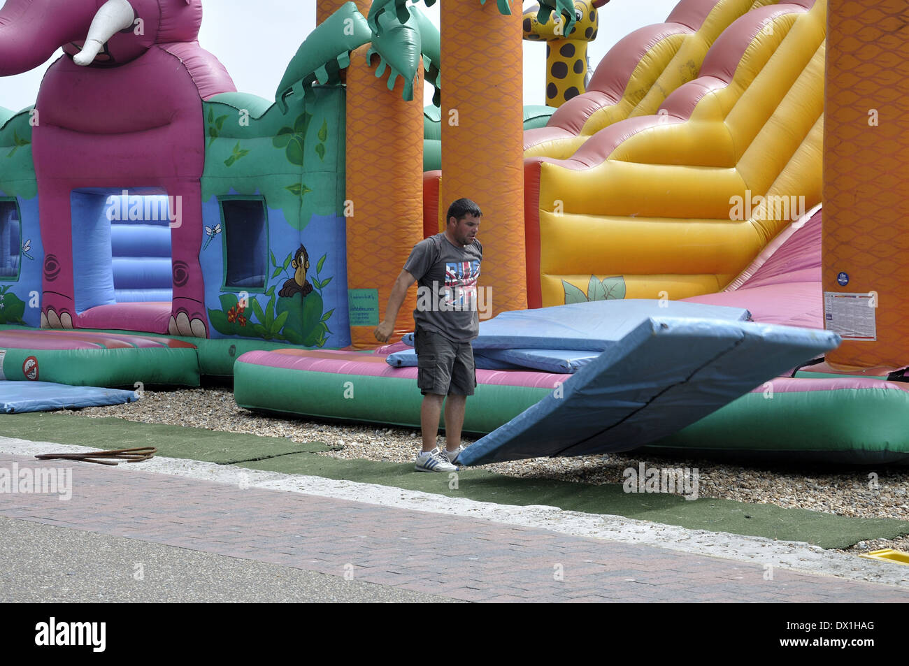 Man dropping safety mat into place in front of inflatable slide Stock ...