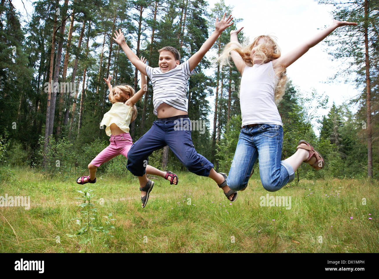 Children jump on lawn in summer forest and enjoy life in sports Stock ...