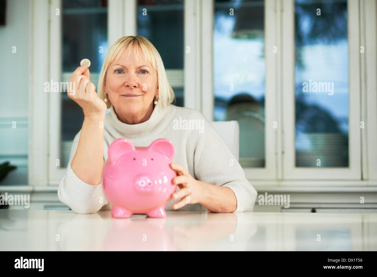 portrait of happy caucasian senior woman saving euro coin into ...