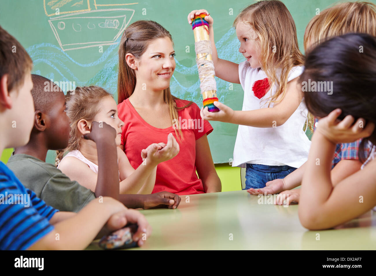 Children in musical education in kindergarten playing with rainmaker ...