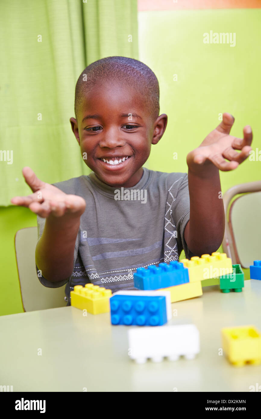 Happy african boy playing in kindergarten with building blocks Stock ...