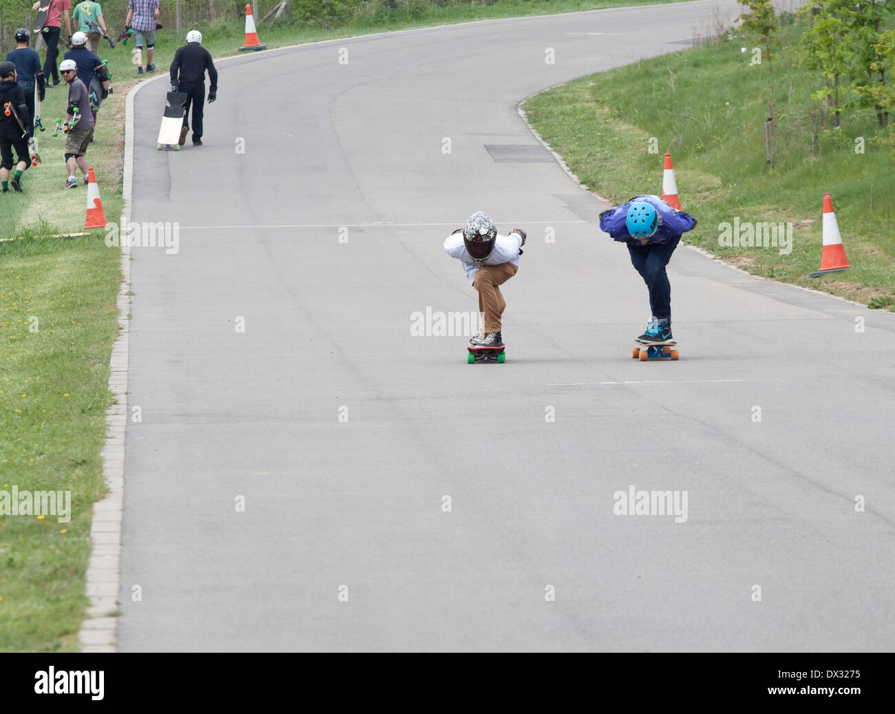Two skateboarders descend in an aerodynamic crouch whilst other walk ...