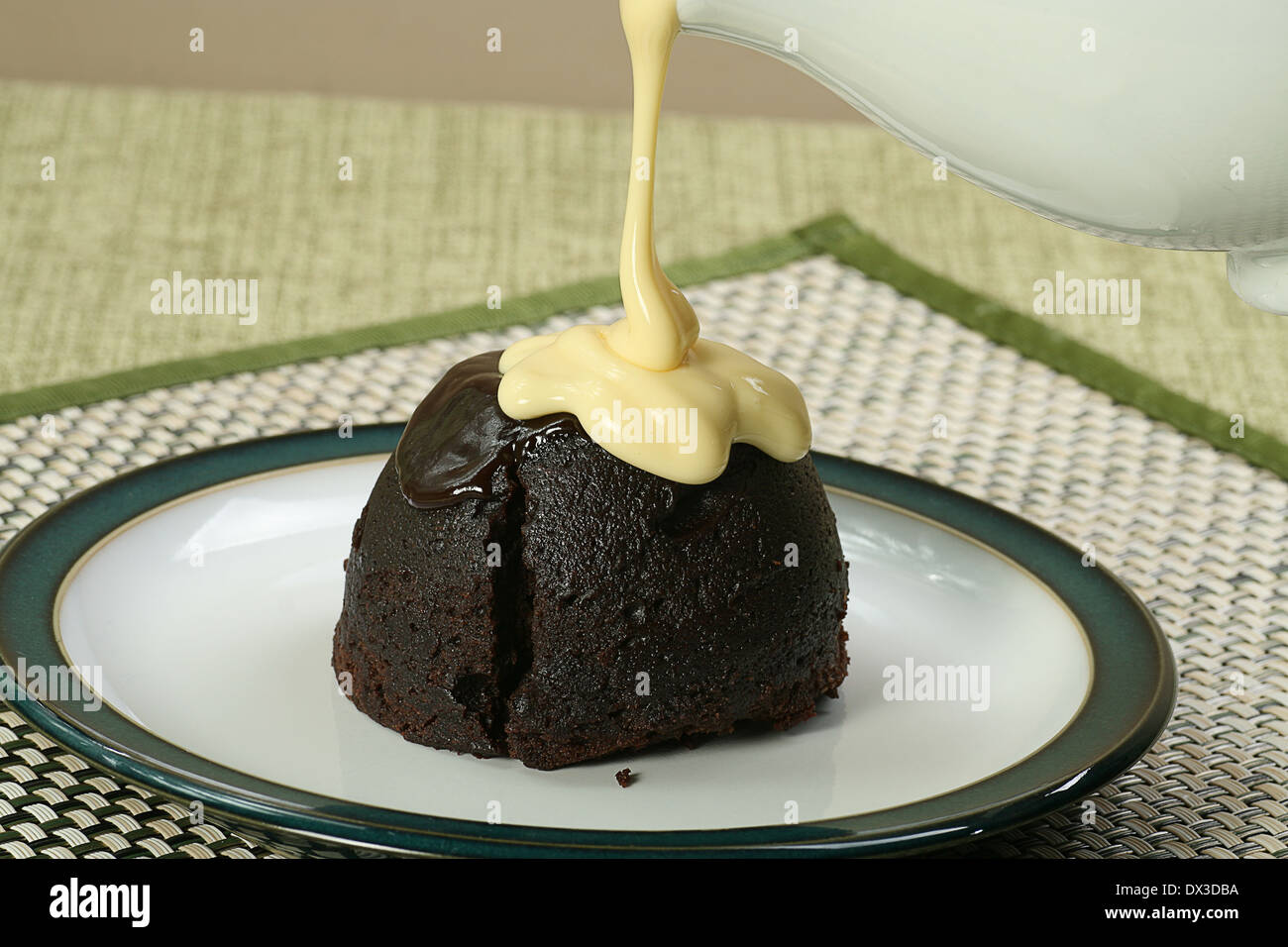 dark chocolate sponge dessert with pouring custard Stock Photo - Alamy