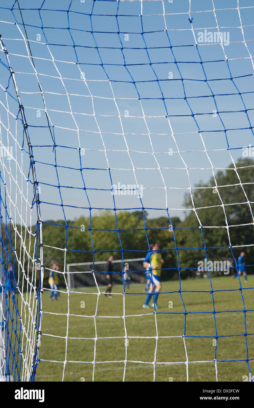 view from behind the goal and focus on the football net with players ...