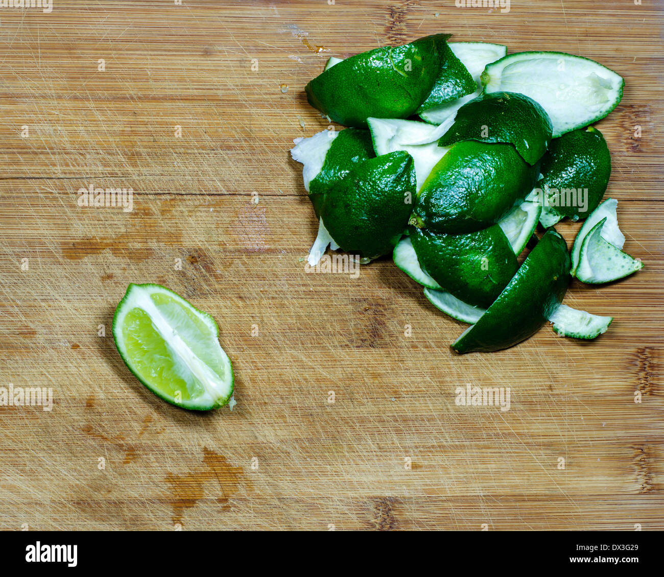 A single piece of cut lime waiting to be peeled next to the peels from ...