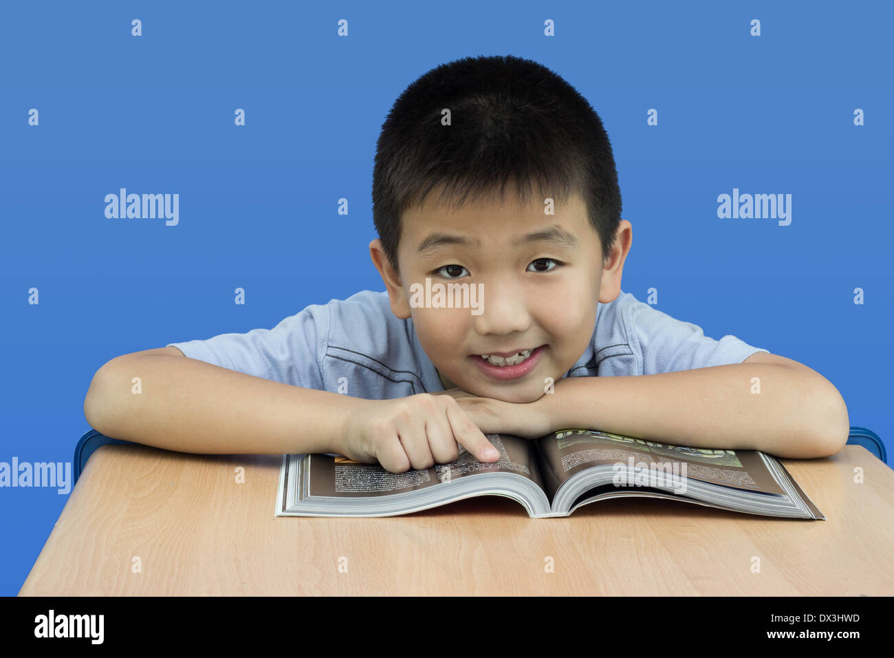Asian boy smile reading book on blue background Stock Photo - Alamy