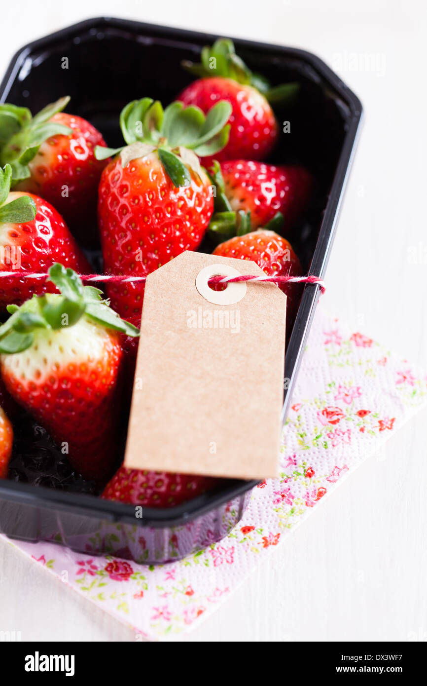 Closeup of fresh strawberries with empty cardboard tag in plastic ...