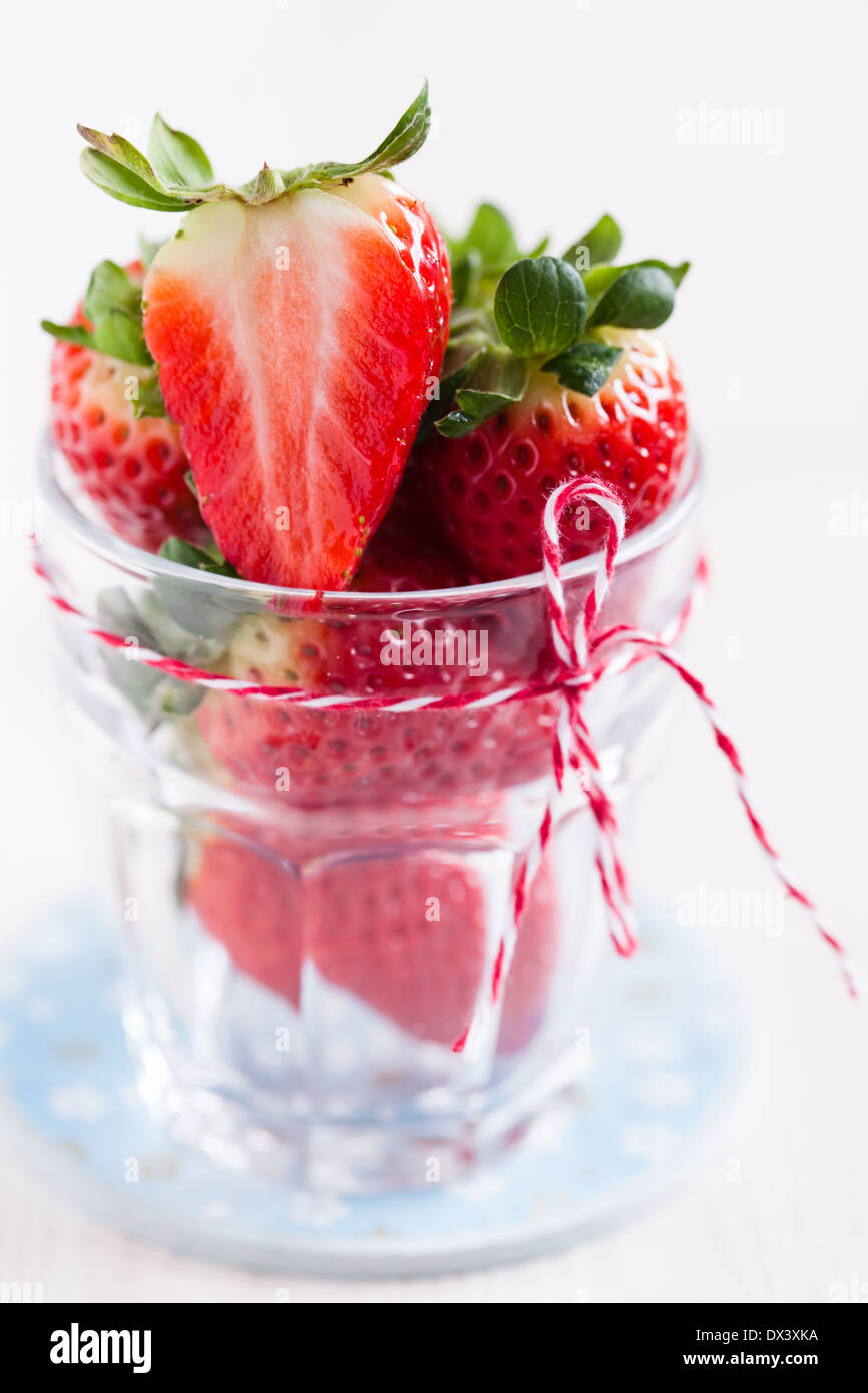 Closeup of fresh strawberries in glass with decorative striped string ...