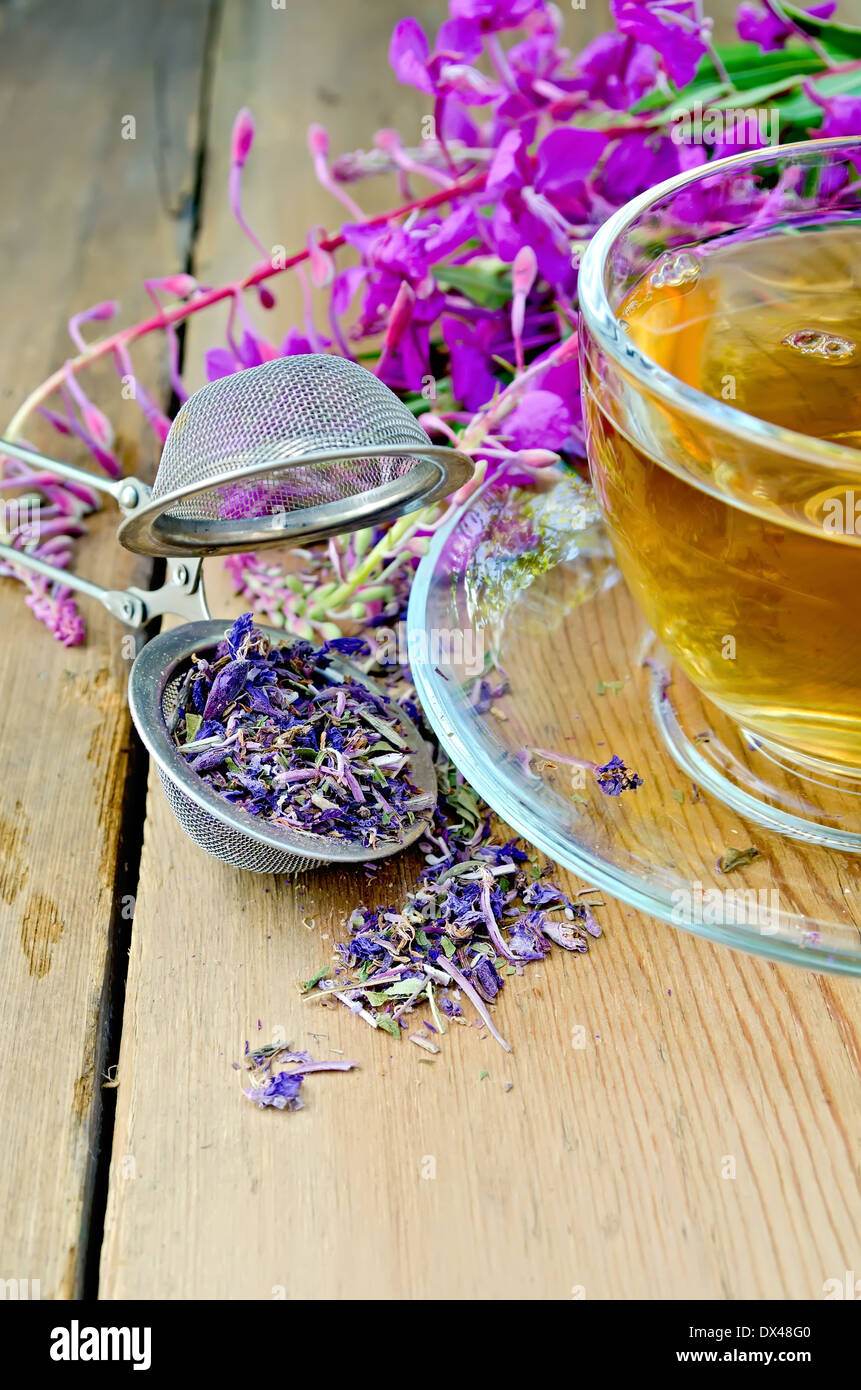 Herbal tea in a glass cup, metal sieve with dry flowers fireweed ...