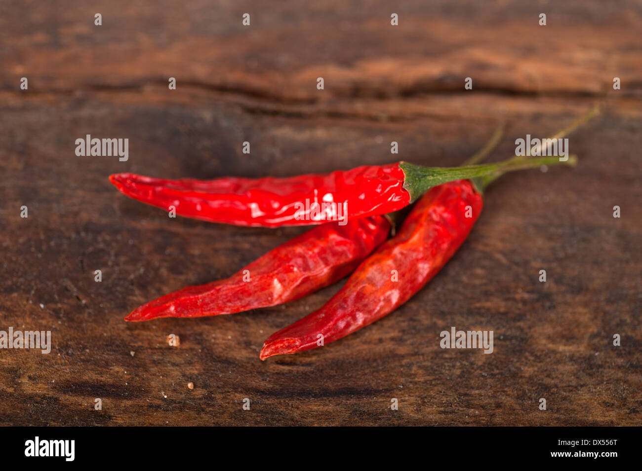 dry red chili peppers over old wood table Stock Photo - Alamy