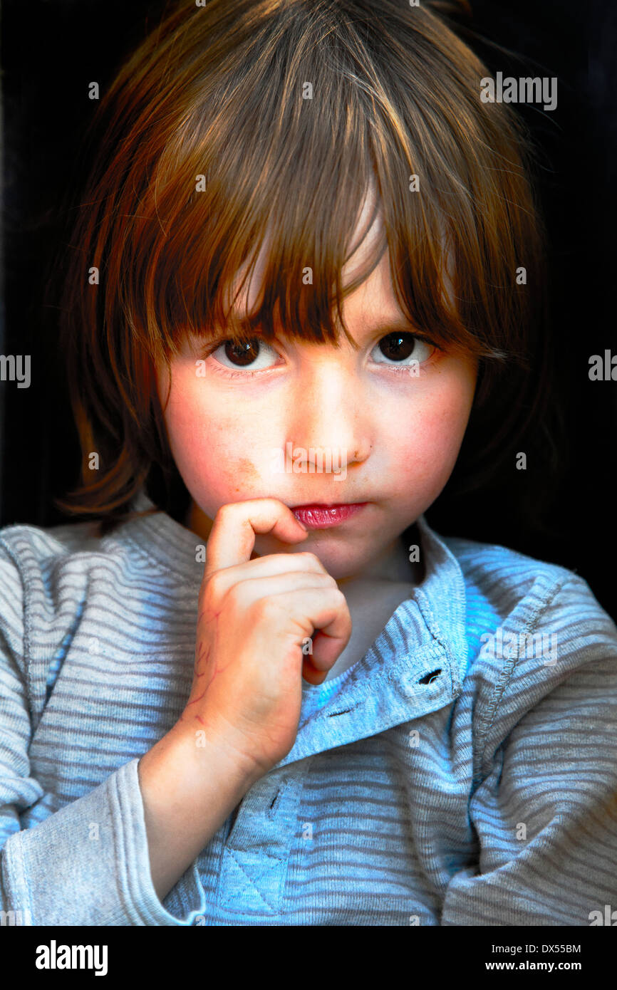 Cute 5 year old boy holding his hand to his mouth Stock Photo - Alamy