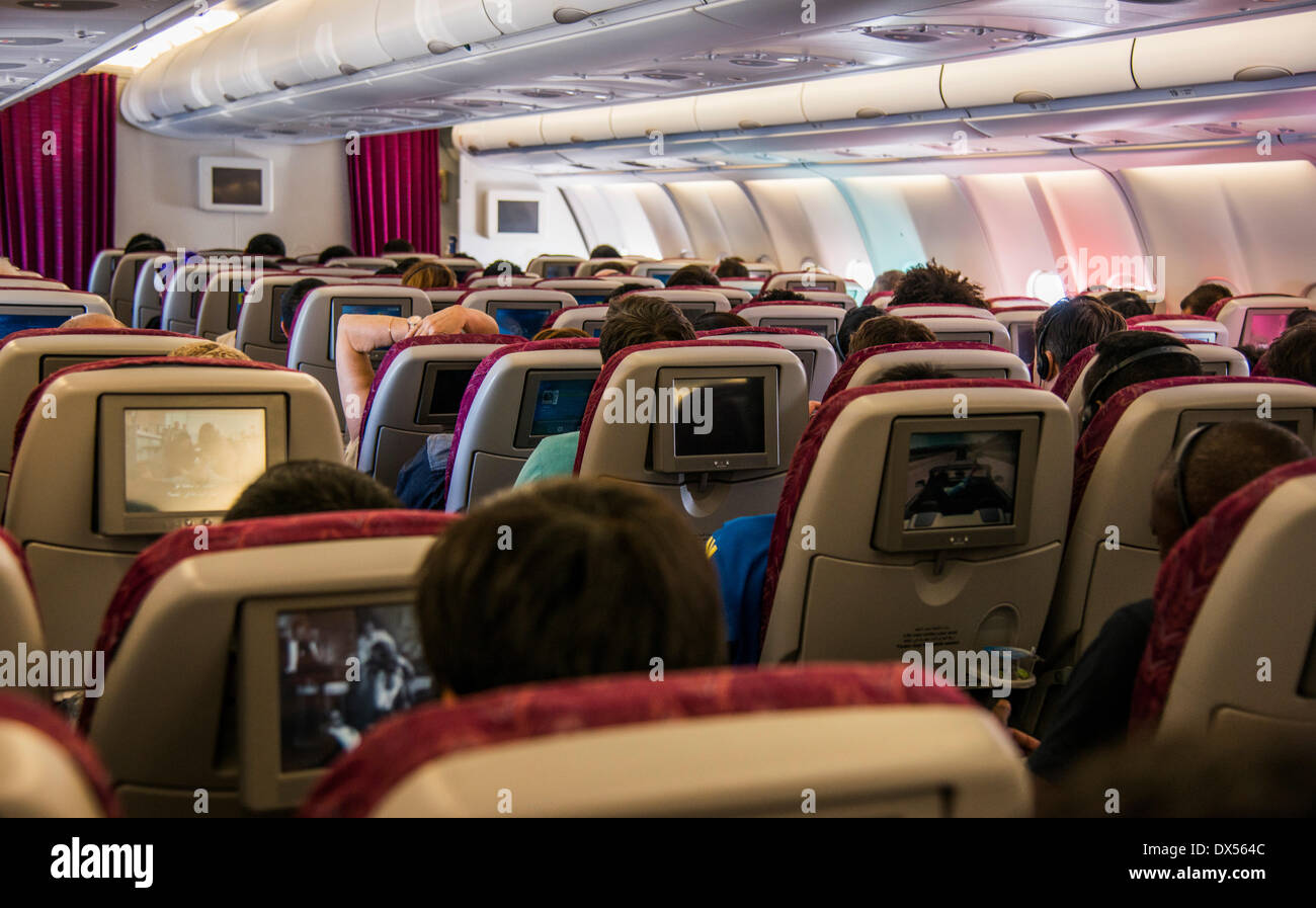 Cabin of a passenger aircraft with entertainment screens and passengers ...