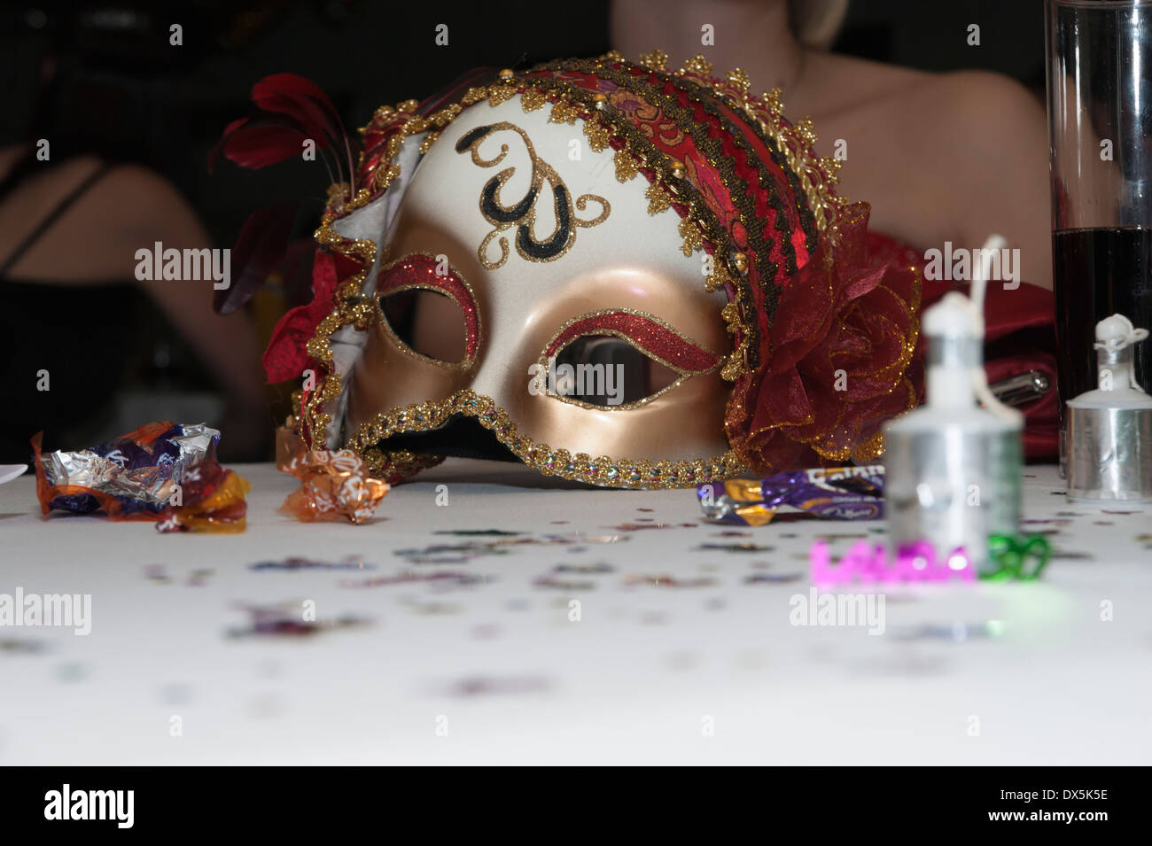 A discarded mask at a party on a table with confetti and poppers Stock ...