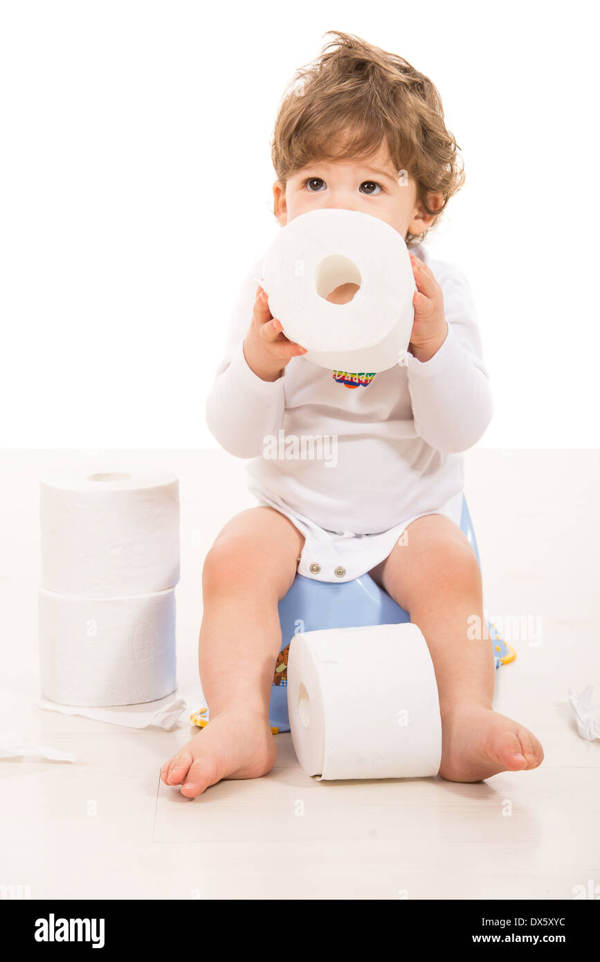 Toddler boy sitting on potty holding rolls paper and looking up Stock ...