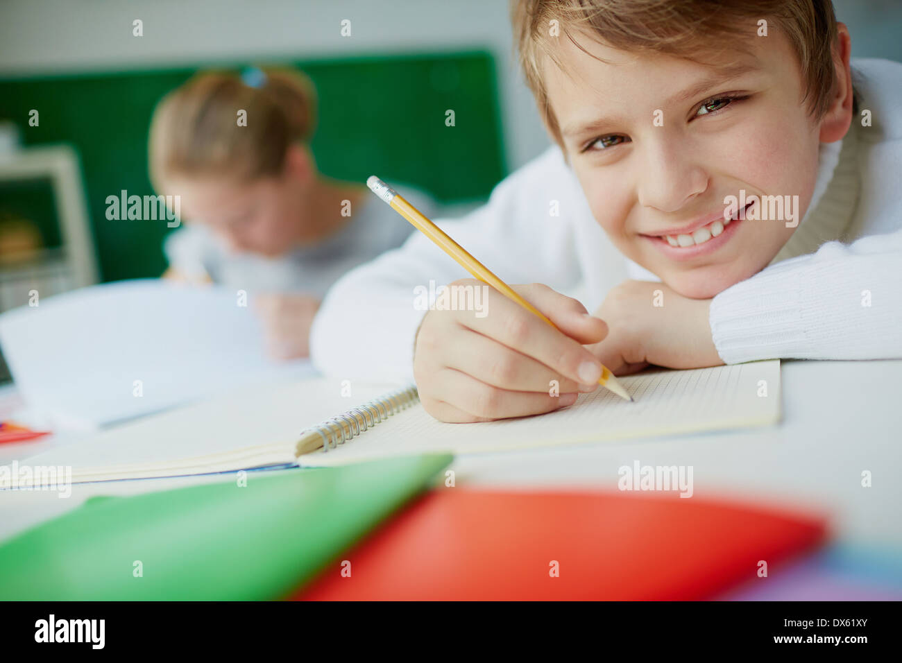 Portrait of cute schoolboy looking at camera while drawing Stock Photo ...