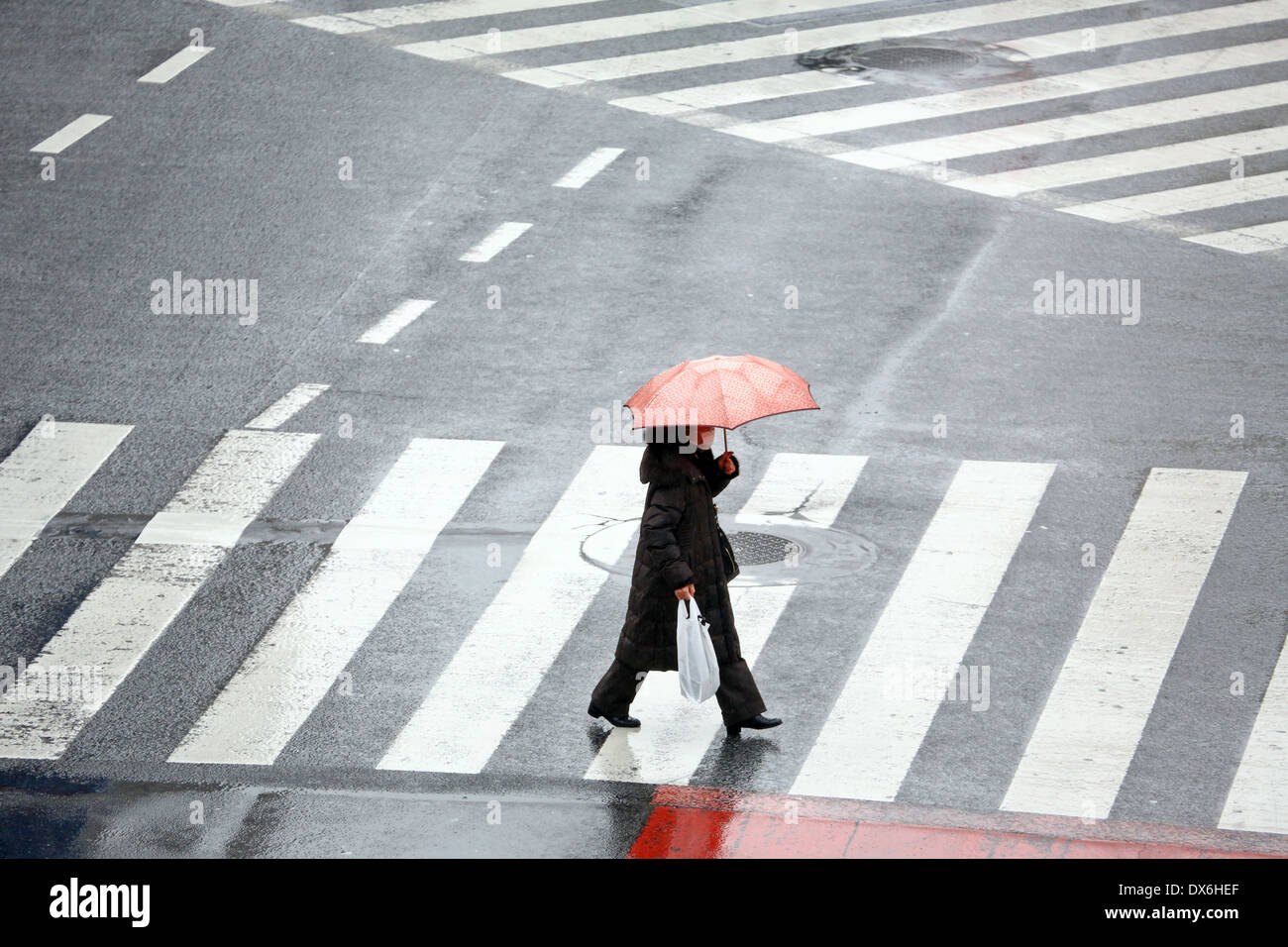 People carrying umbrellas in the rain walking across the pedestrian ...