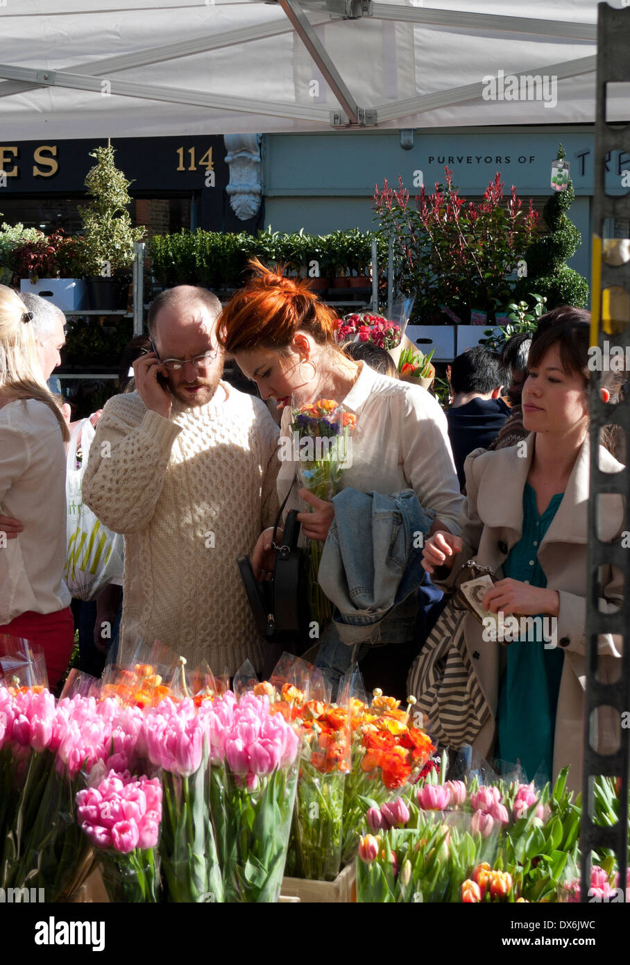A couple shopping for tulips in Columbia Road Flower Market on a sunny ...