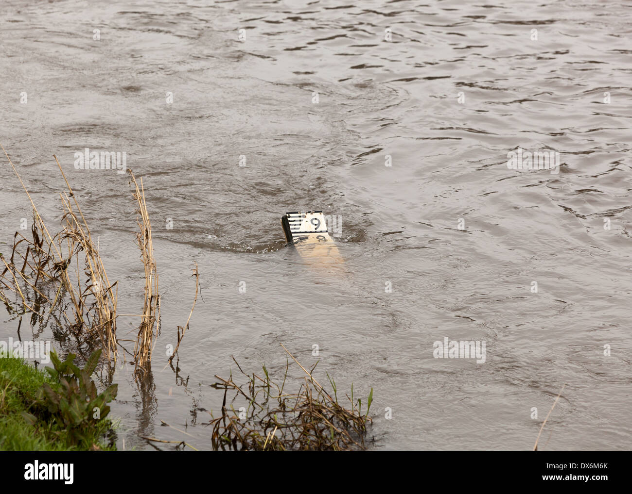 A water level measuring gauge washed over by a fast flowing river Tame ...