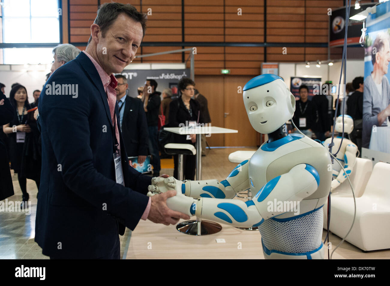 Lyon, France - 19 March 2014: An exhibitor holds the hands of NAO Robot ...