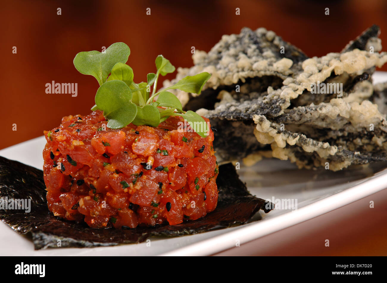 Raw ahi tuna tartare appetizer atop a sheet of nori and garnished with ...