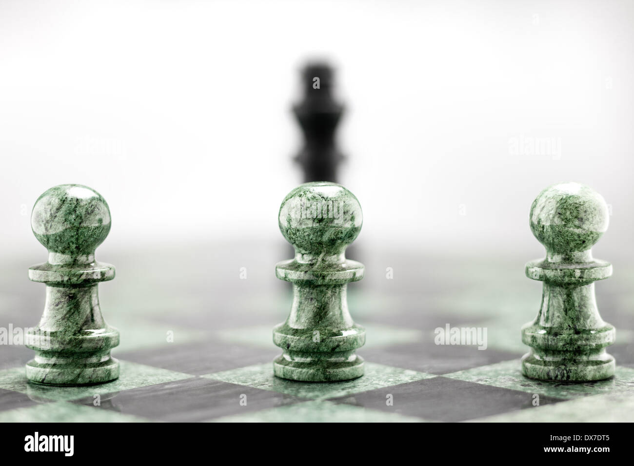 Three pawns in a raw standing in front of king shape Stock Photo - Alamy