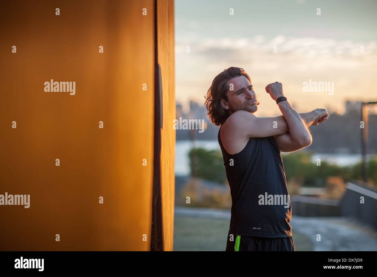 A young man having a pre-workout stretch before an early-morning ...