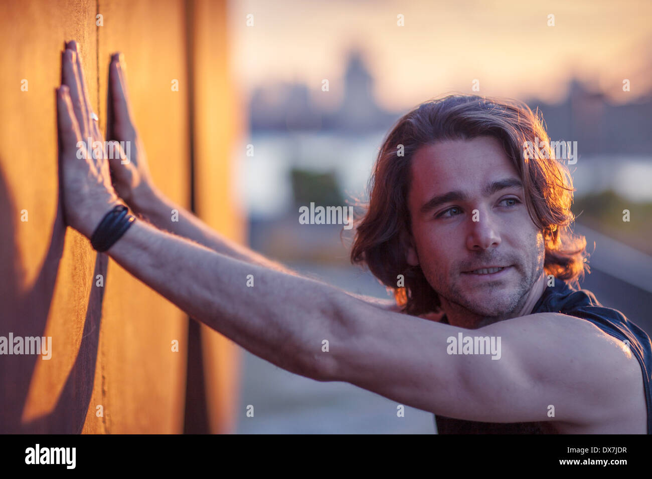 A young man having a pre-workout stretch before an early-morning ...